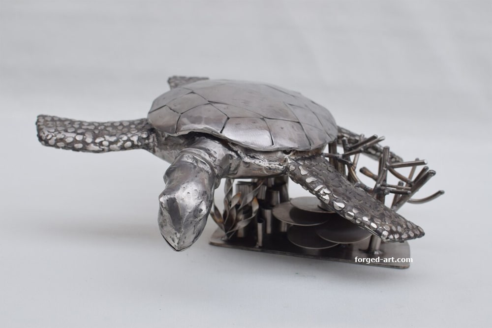A forged sculpture of a sea turtle swimming among the waves